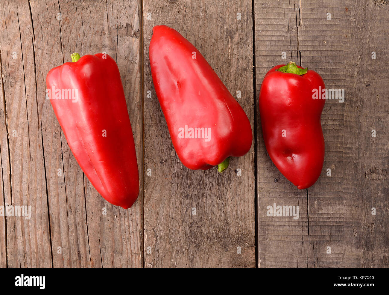 Three red fresh paprika on an old used barn wood Stock Photo - Alamy