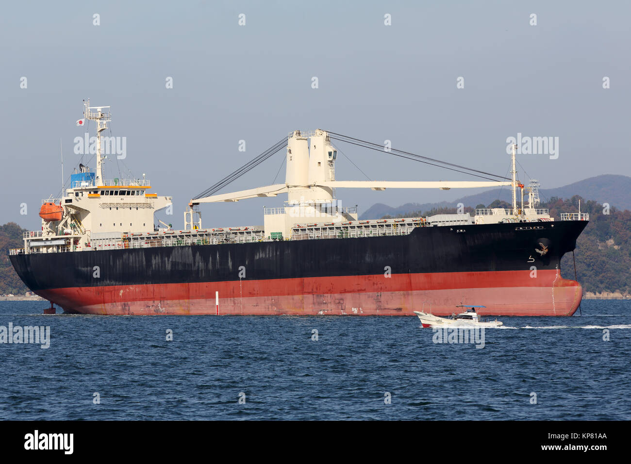 large cargo ship and fishing boat against blue sky Stock Photo - Alamy