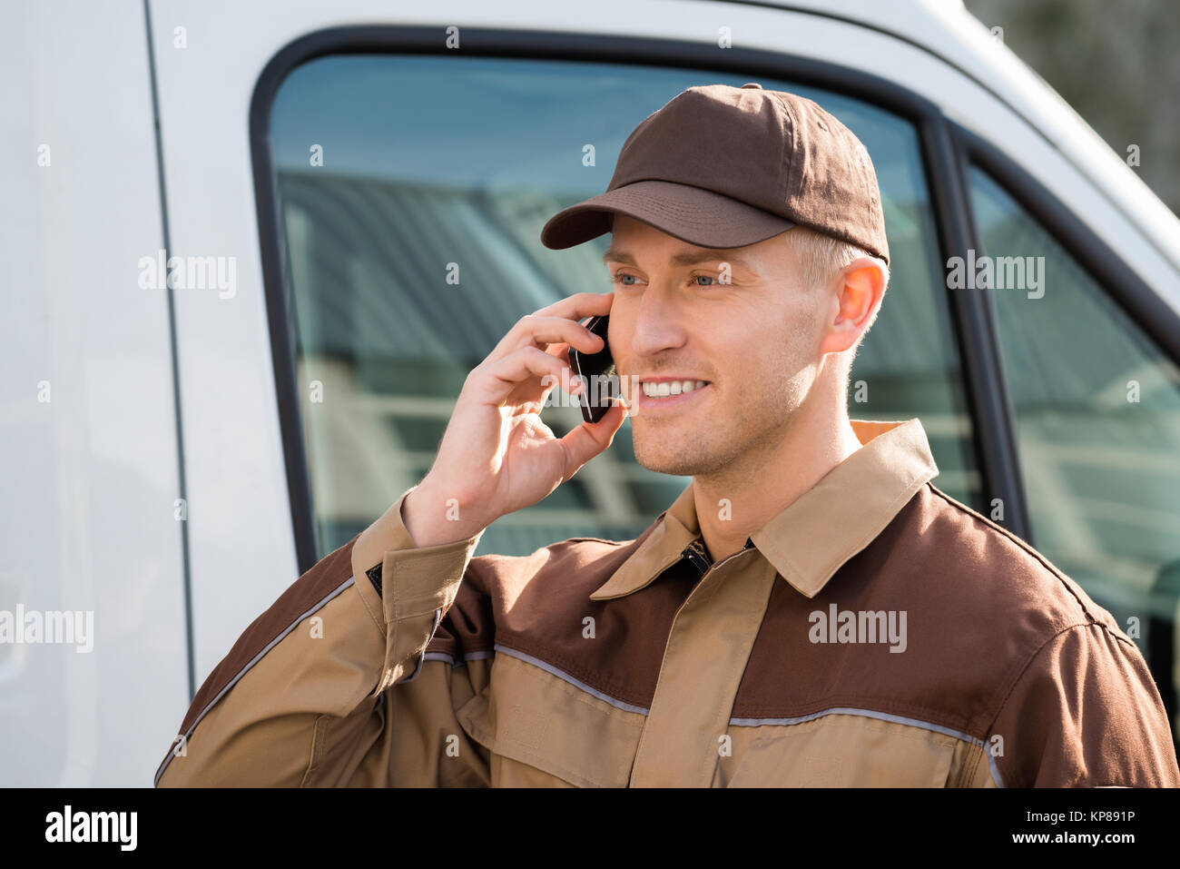 Smiling Delivery Man Using Mobile Phone Against Truck Stock Photo - Alamy