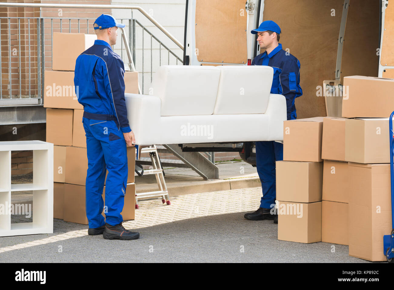 Movers Carrying Sofa Outside Truck On Street Stock Photo - Alamy