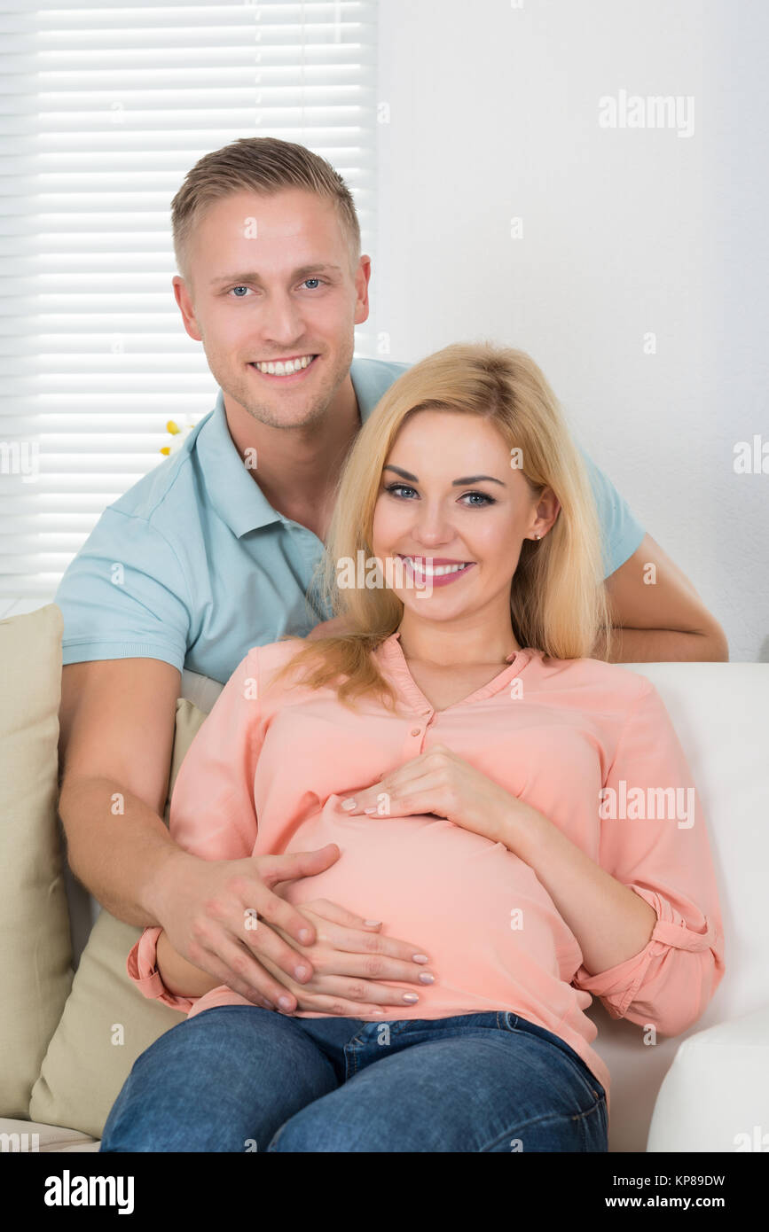 Happy Expecting Couple Sitting On Sofa At Home Stock Photo - Alamy