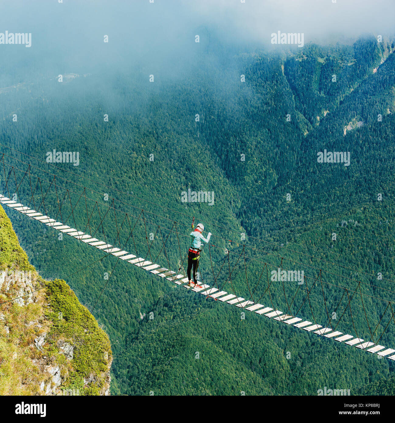 Woman crossing the abyss on the rope bridge Stock Photo - Alamy