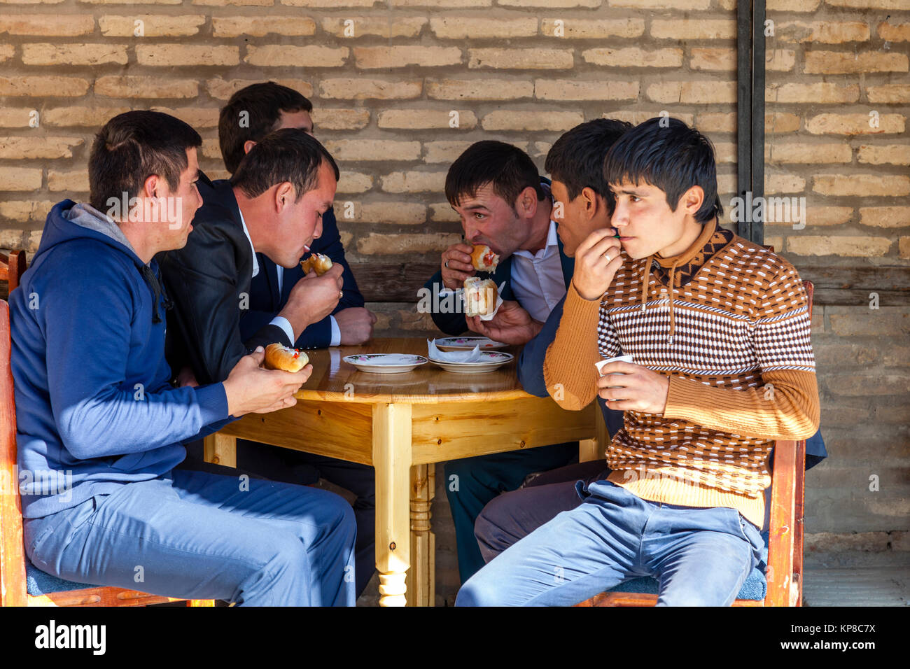 A Group Of Uzbek Men Eating Hot Dogs Outside A Cafe, Khiva, Uzbekistan ...