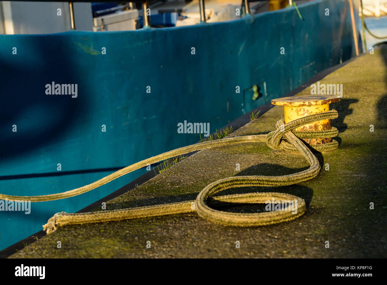 Bollard in the fishing port on the wharf. The wrapped rope mooring ...