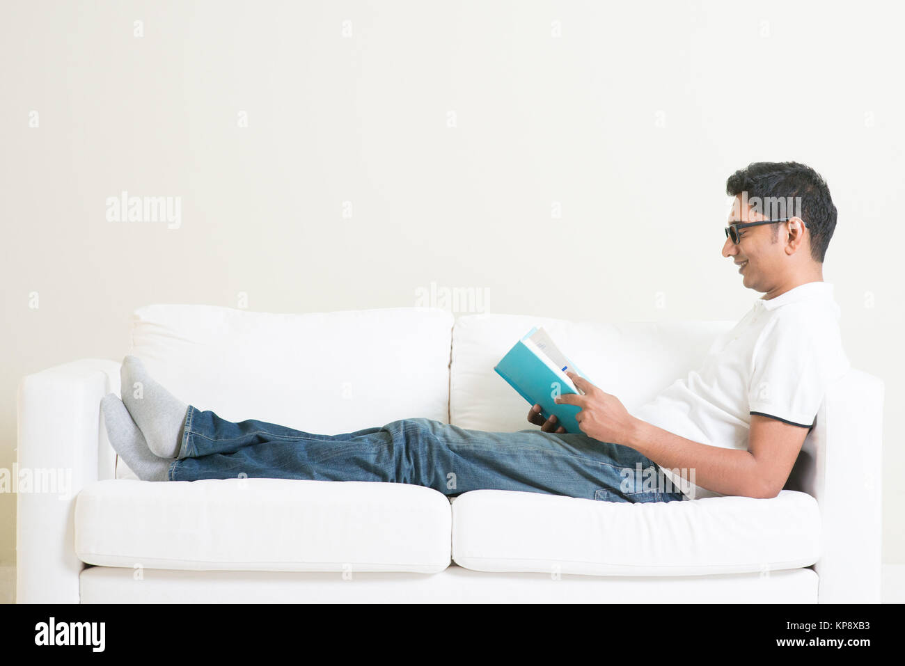 Asian man reading book on couch Stock Photo - Alamy