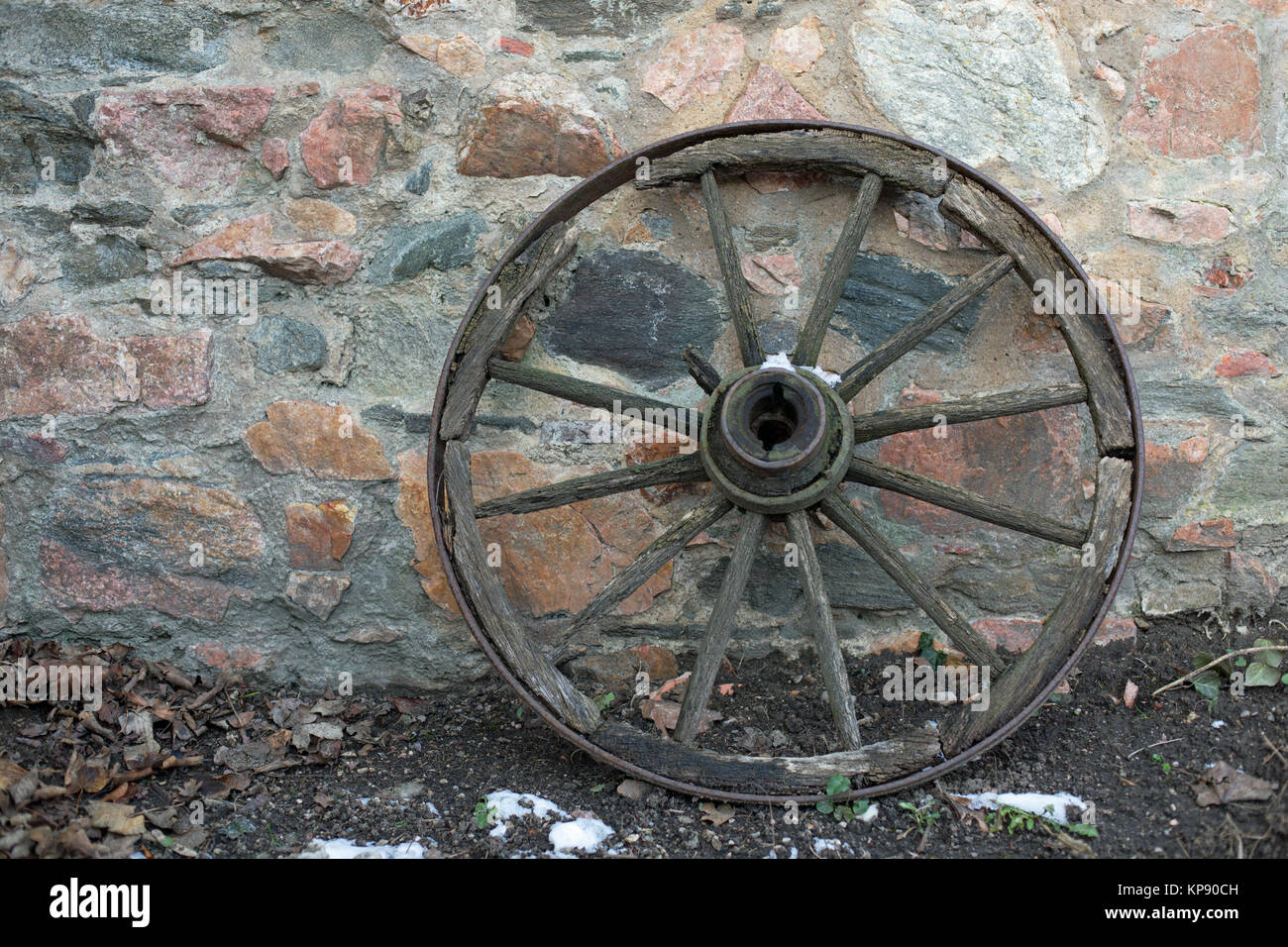 Old wooden wagon wheel on a stone wall in winter Stock Photo - Alamy