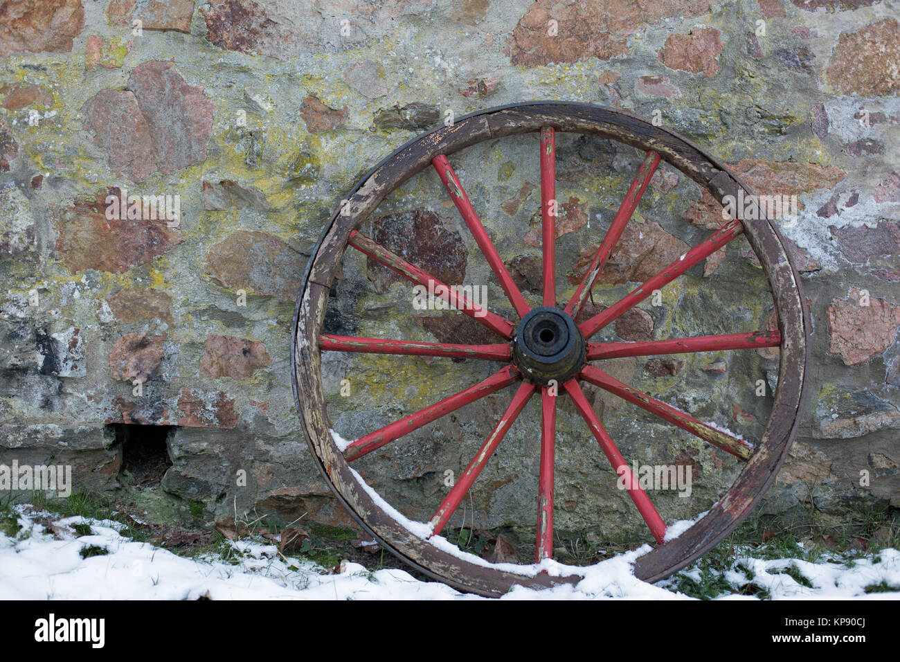 Old wooden wagon wheel on a stone wall in winter Stock Photo - Alamy