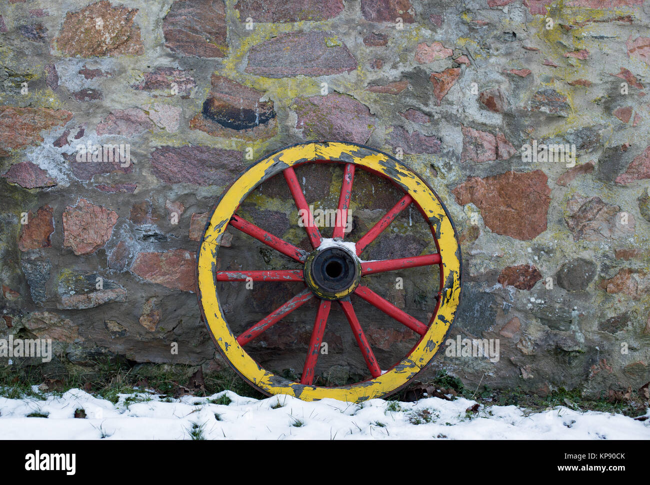 old wooden wagon wheel on a stone wall in winter Stock Photo - Alamy