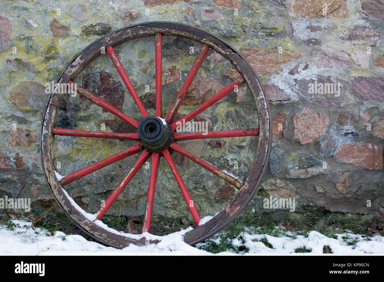 Old wooden wagon wheel on a stone wall in winter Stock Photo - Alamy