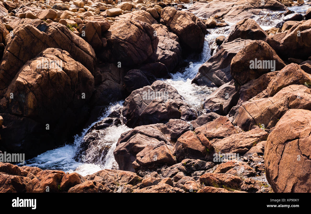 Stream flowing and splashing among bare red rocks Stock Photo - Alamy