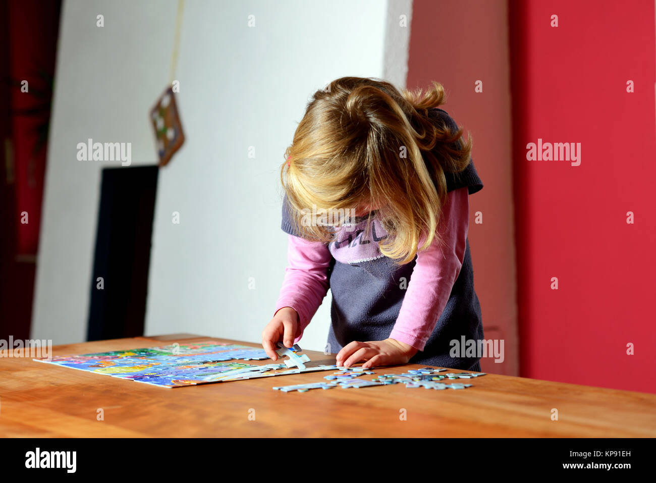 little blond girl doing a jigsaw puzzle Stock Photo - Alamy