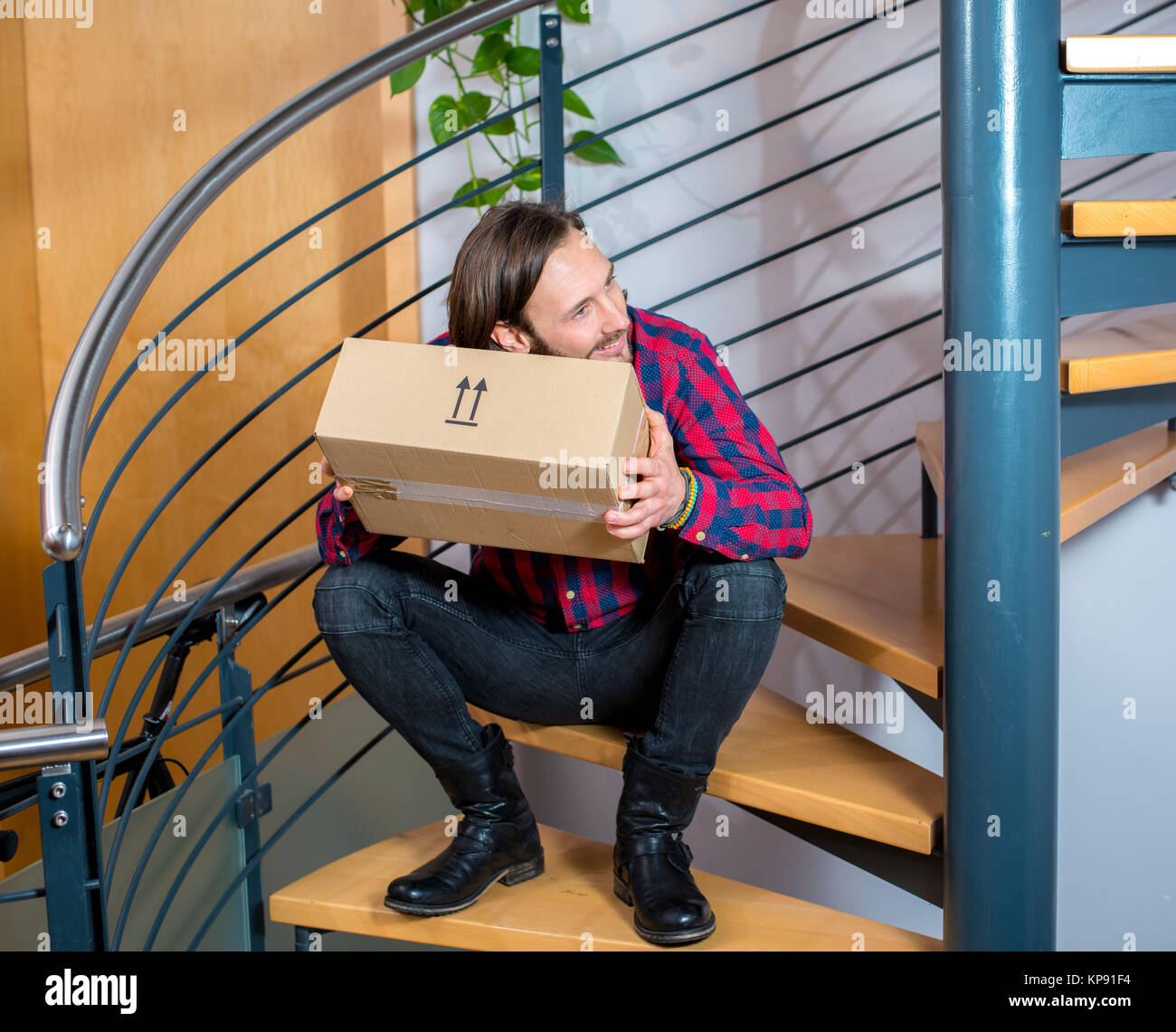 young man sitting in corridor and opening a package Stock Photo - Alamy