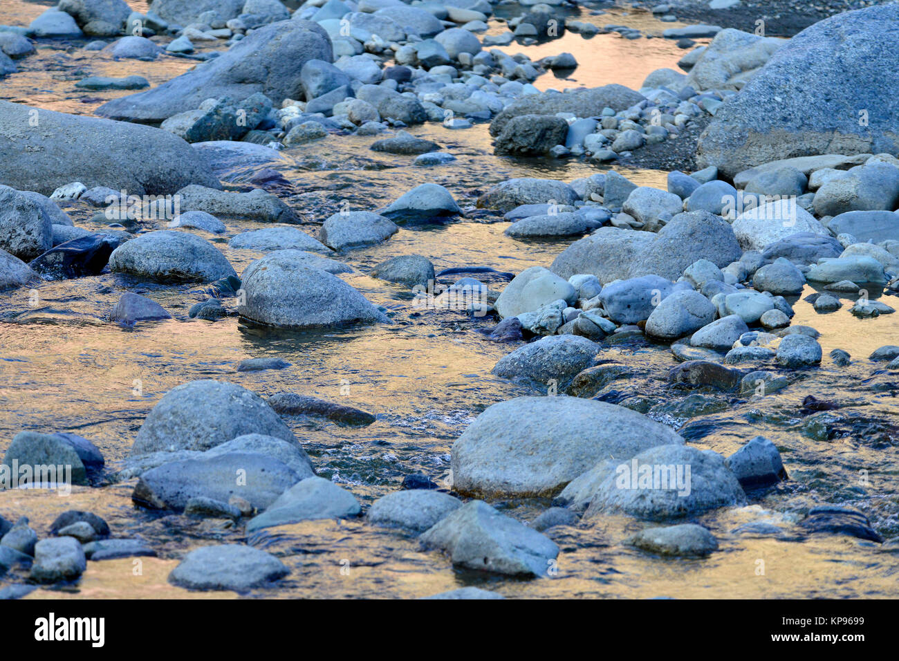 Blue boulders of pebbles and cobblestones in the riverbed, the water is ...