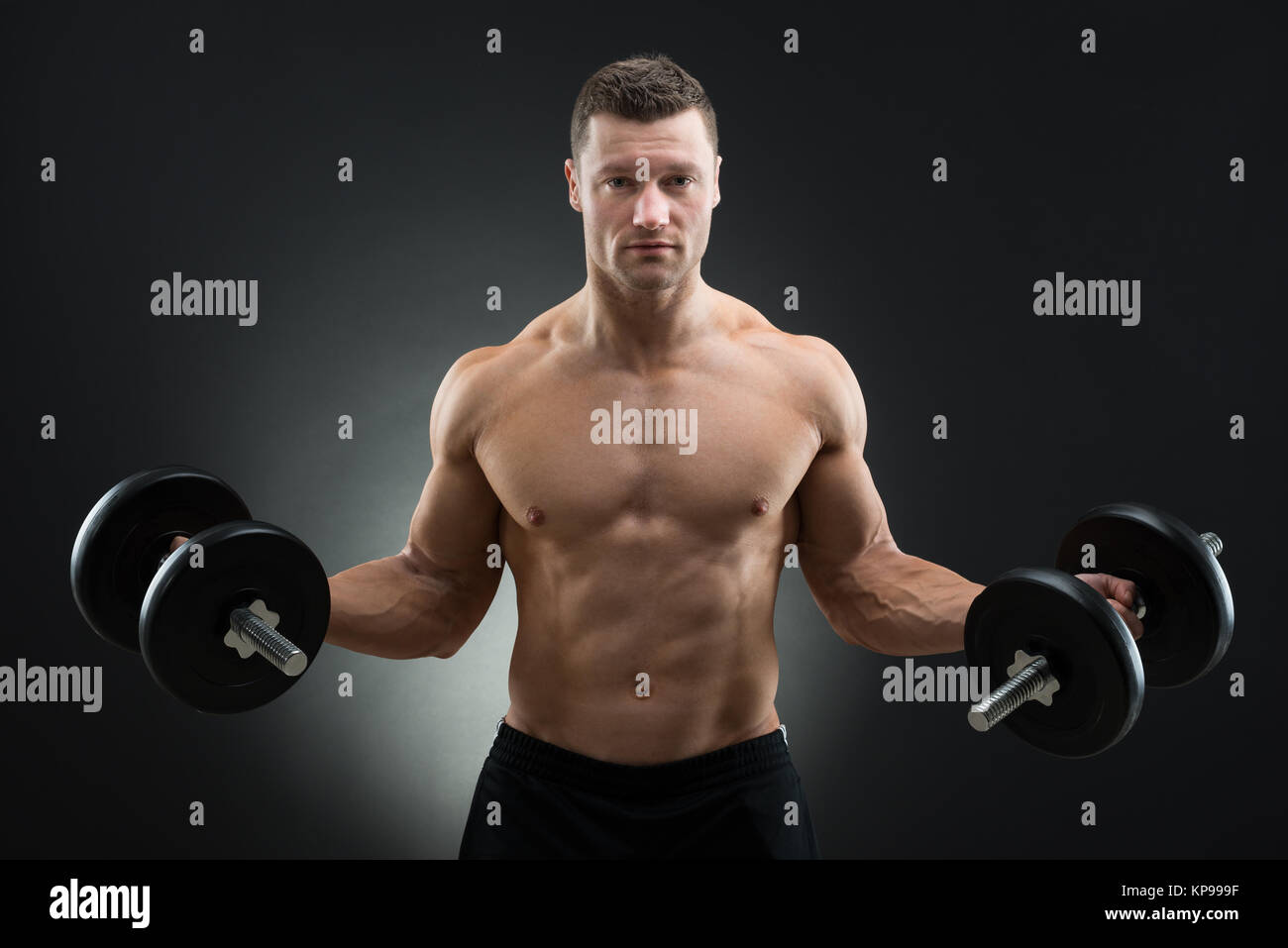 Confident Muscular Man Holding Dumbbells Stock Photo - Alamy