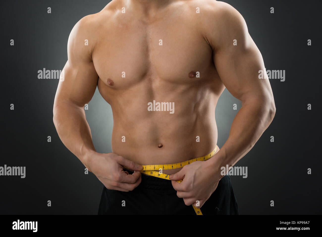 Midsection Of Muscular Man Measuring Waist Stock Photo - Alamy