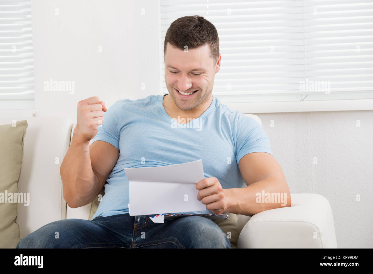 Man Clenching Fist While Reading Letter On Sofa Stock Photo - Alamy
