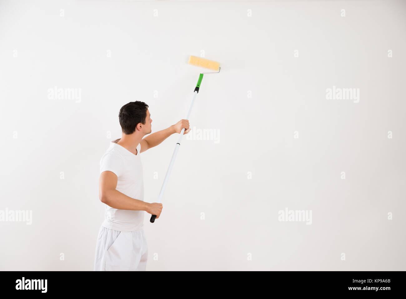 Man Using Paint Roller On White Wall Stock Photo - Alamy