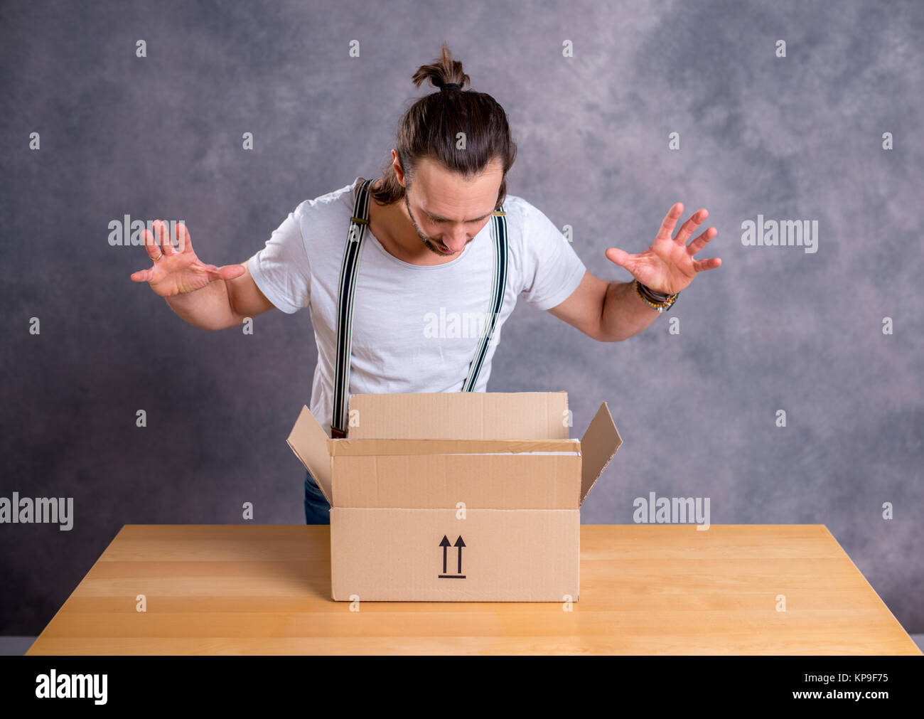 young man opening a package in front of gray background Stock Photo - Alamy
