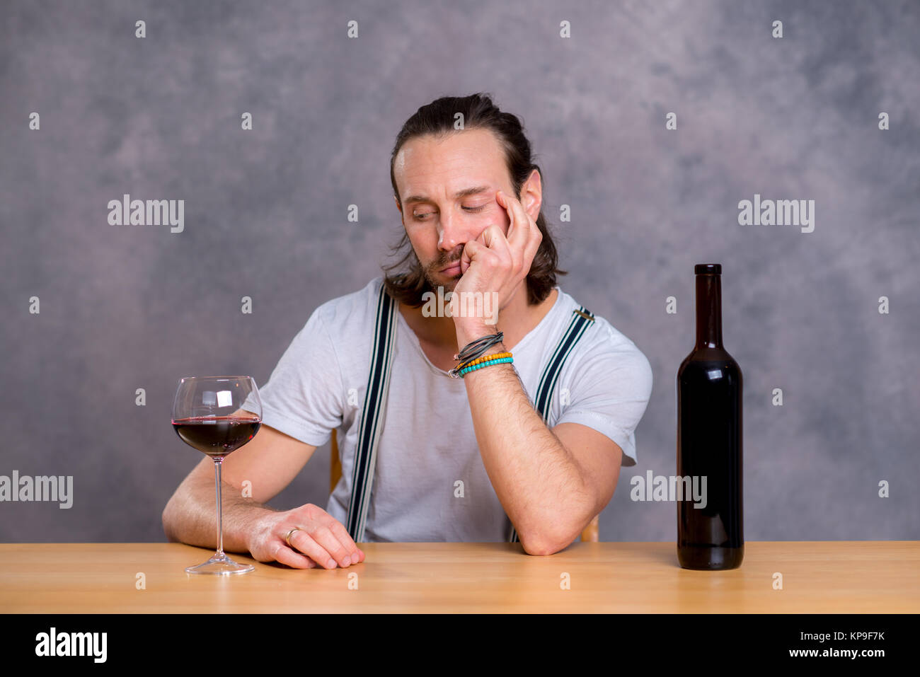 young man sitting bored at the table and drinking red wine Stock Photo ...