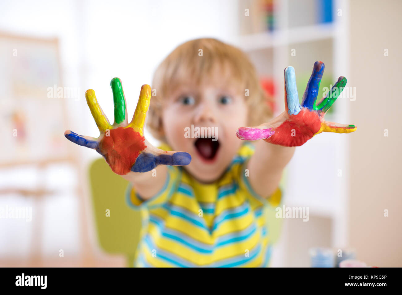Cheerful child boy showing hands painted in bright colors. Focus on ...