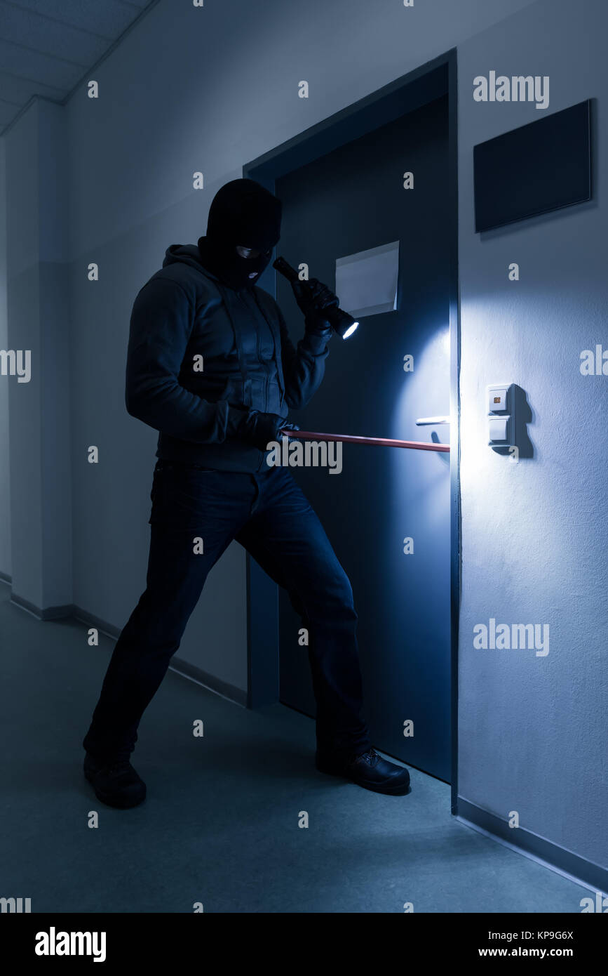 Thief With Flashlight Trying To Break Office Door Stock Photo - Alamy