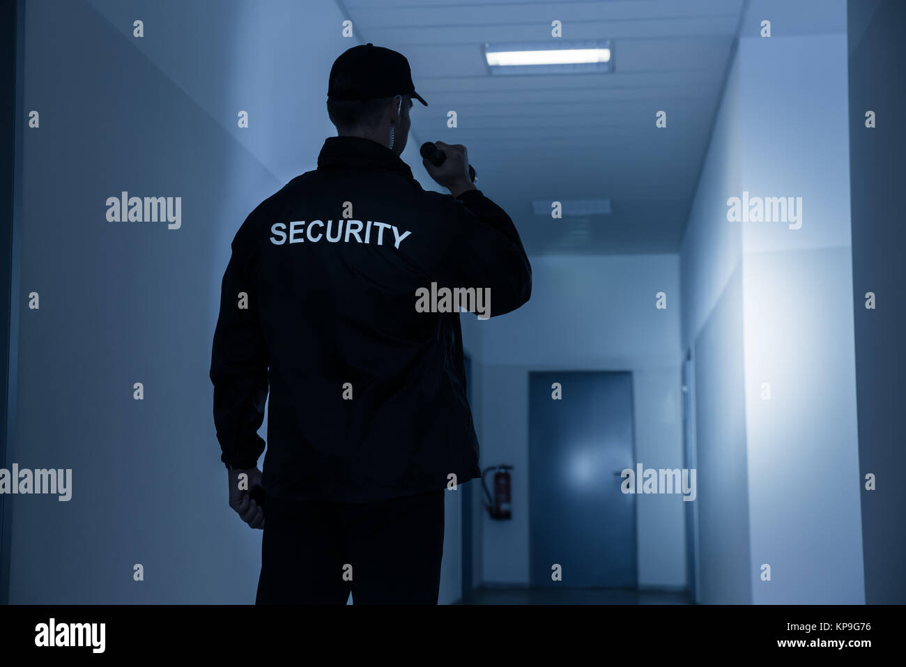 Security Guard With Flashlight In Building Corridor Stock Photo - Alamy