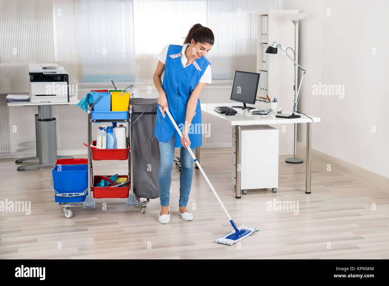 Happy Female Janitor Mopping Floor In Office Stock Photo - Alamy