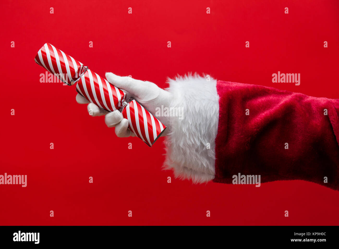Santa Claus hand holding a Christmas cracker Stock Photo - Alamy