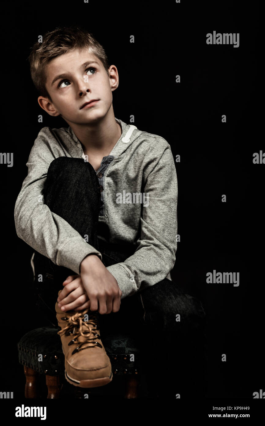 Pensive young boy sitting thinking Stock Photo - Alamy