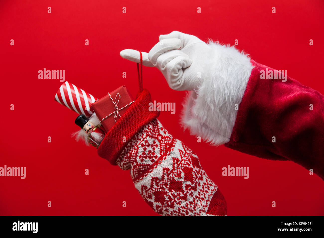 Santa Claus hand holding a Christmas present Stock Photo - Alamy