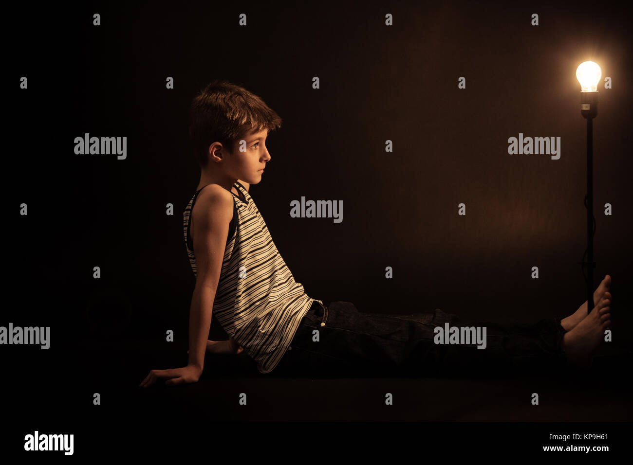 Thoughtful Boy Looking at the Light Bulb on Stand Stock Photo - Alamy