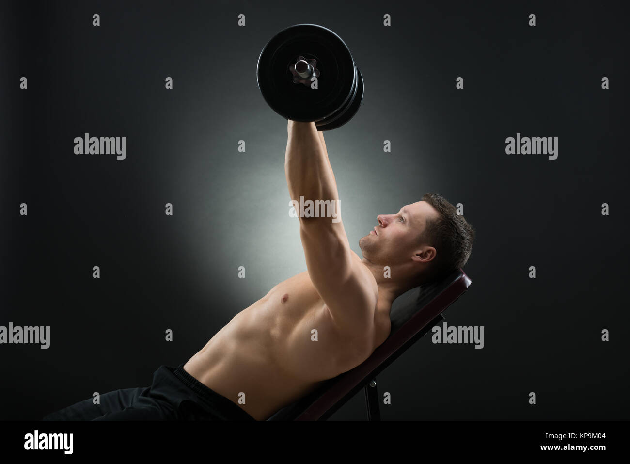 Determined Man Lifting Dumbbells While Reclining On Chair Stock Photo ...