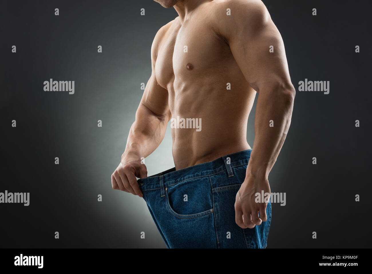 Midsection Of Muscular Man In Old Jeans Showing Weight Loss Stock Photo ...