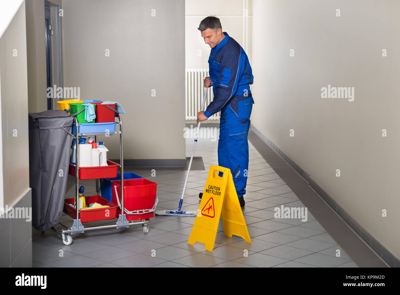 Male Worker With Broom Cleaning Corridor Stock Photo - Alamy