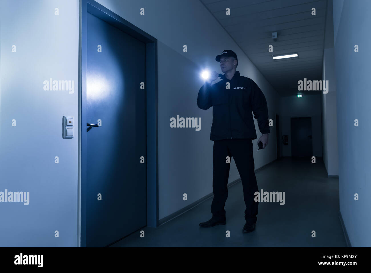 Security Guard With Flashlight Standing In Front Of Door Stock Photo ...