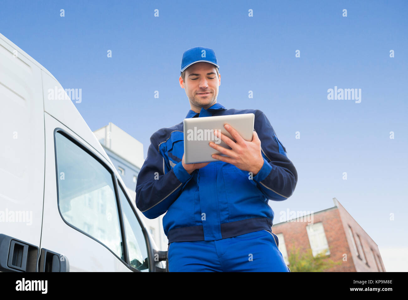 Delivery Man Using Digital Tablet By Truck Against Sky Stock Photo - Alamy