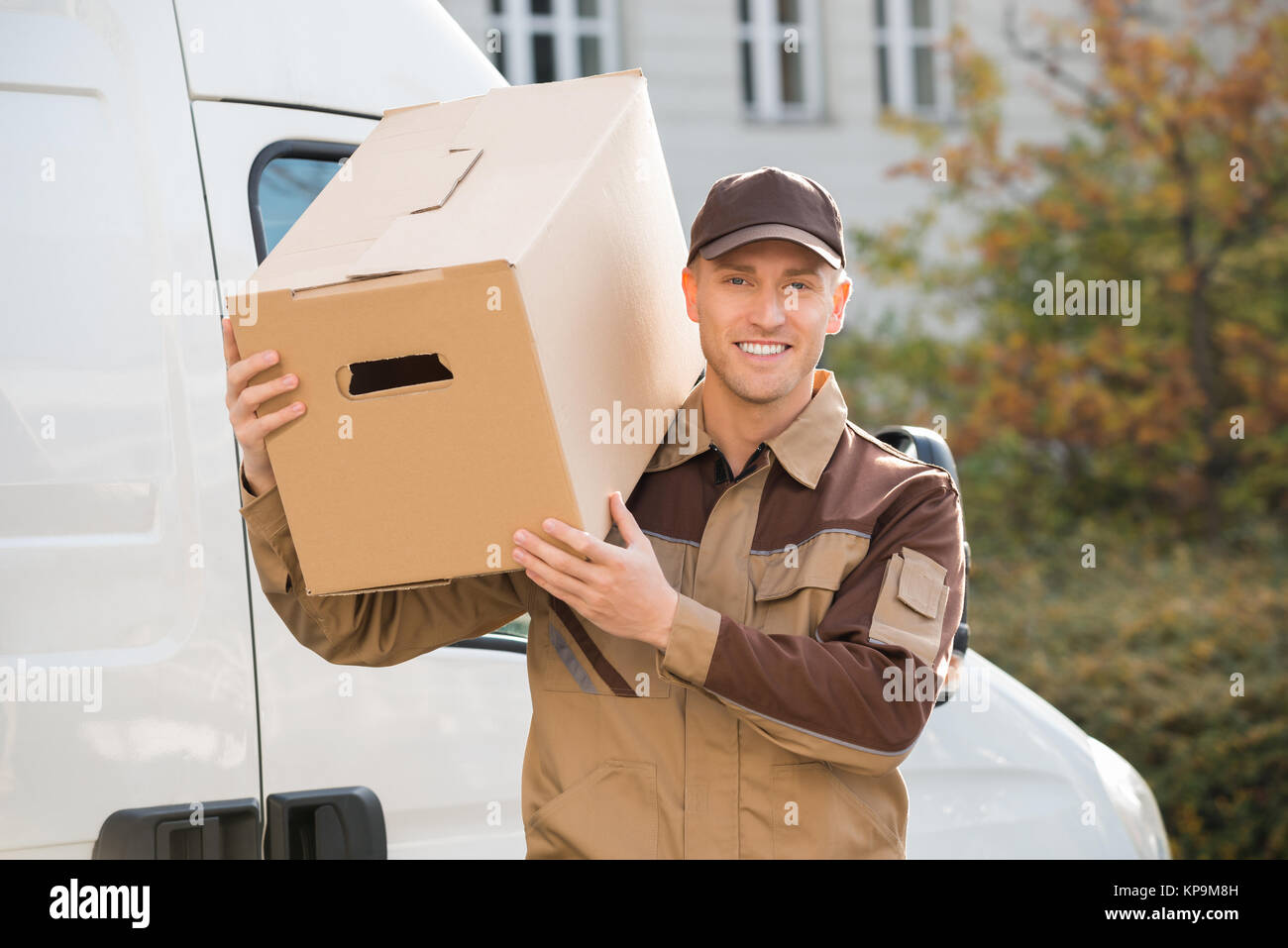 Delivery Man Carrying Cardboard Box On Shoulder Stock Photo - Alamy