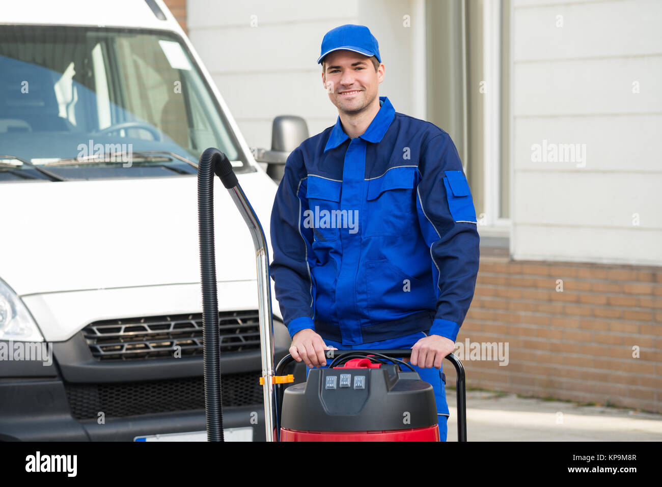 Confident Janitor Standing With Vacuum Cleaner Stock Photo - Alamy