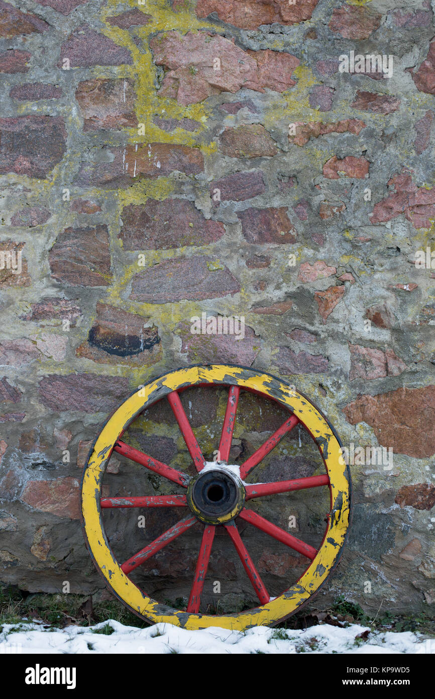 Old wooden wagon wheel on a stone wall in winter Stock Photo - Alamy
