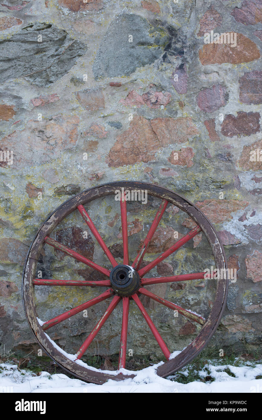 old wagon wheel wooden to a stone wall in winter Stock Photo - Alamy