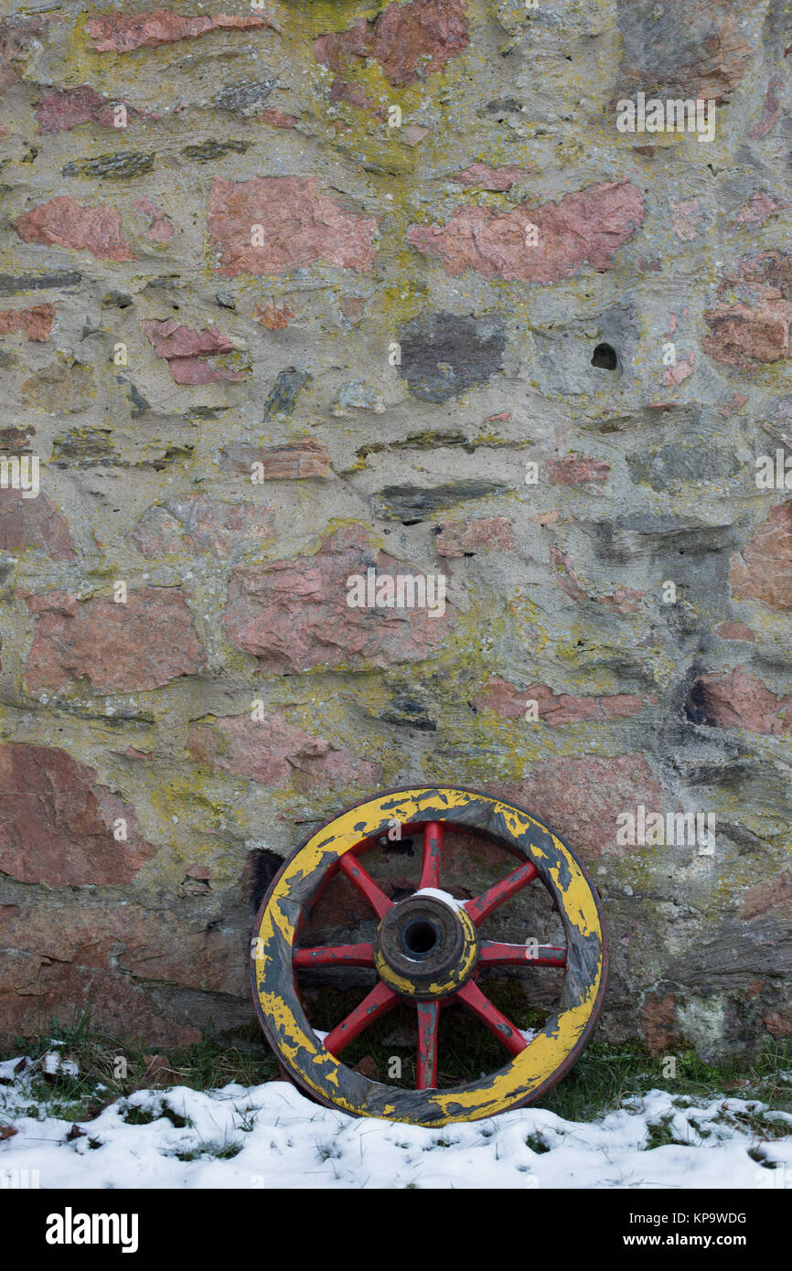 Old wooden wagon wheel on a stone wall in winter Stock Photo - Alamy