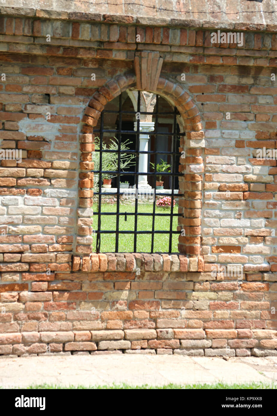 medieval Window with metal grating in the middle of the brick wall of ...