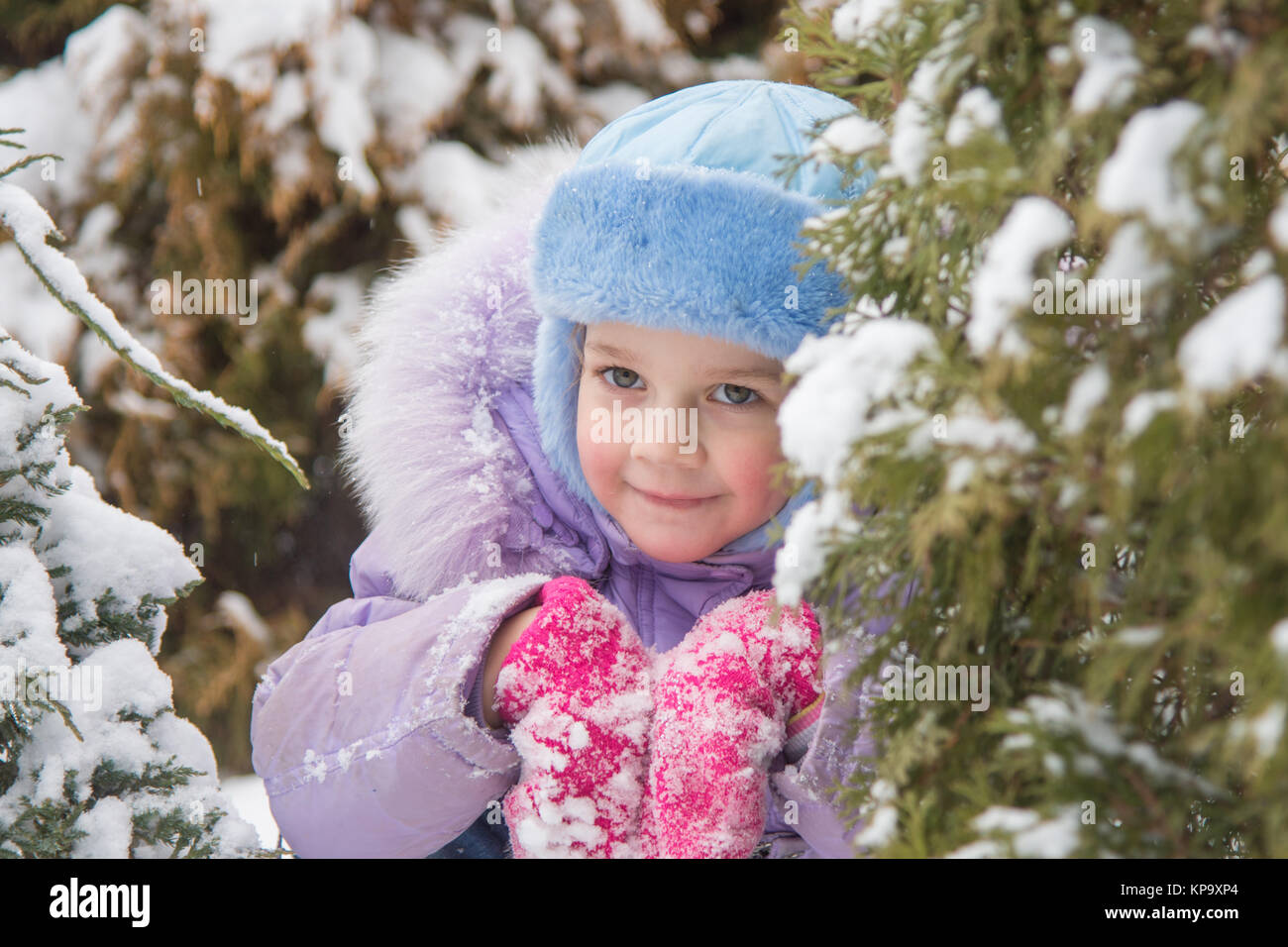Joyful five years girl hiding in the snow-covered fur-trees Stock Photo ...