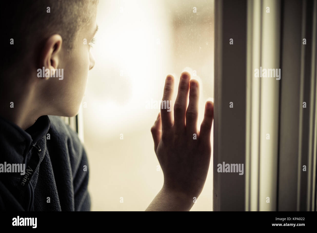 Sad Boy Looking Outside While Holding Glass Window Stock Photo - Alamy