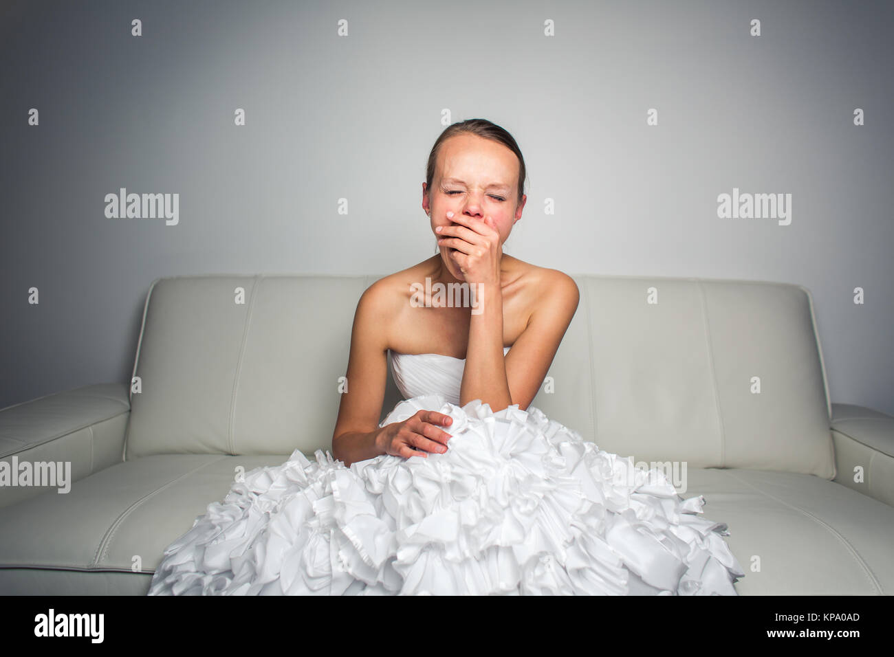 Super tired gorgeous bride sitting on a sofa after a long wedding day ...