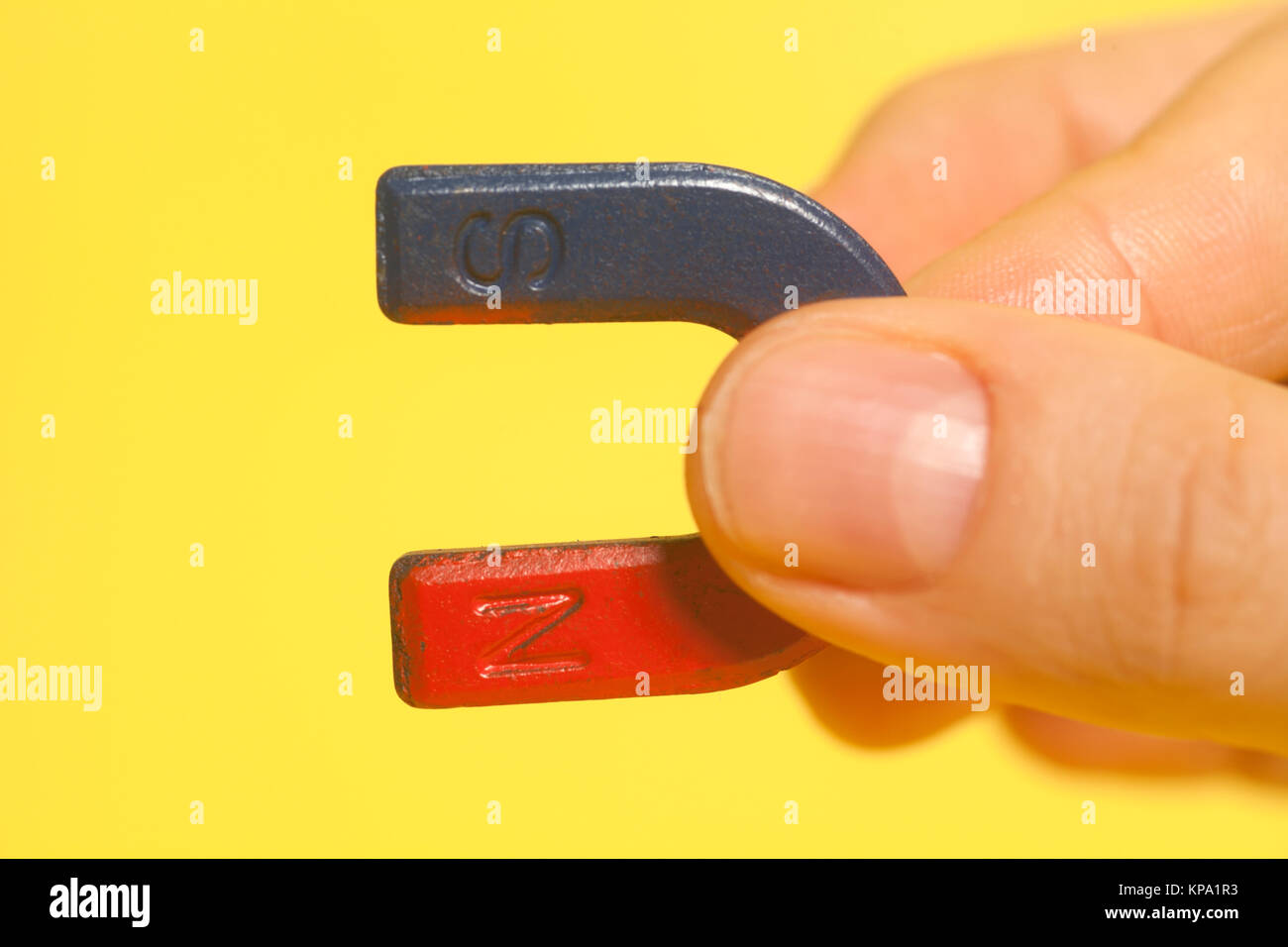 Horseshoe magnet holding hand on a yellow background Stock Photo - Alamy