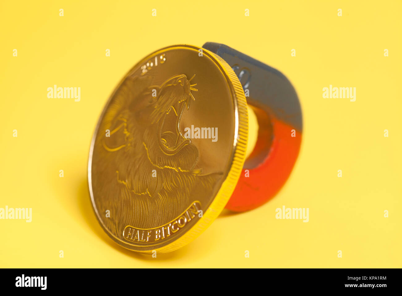 Half bitcoin with lion end horseshoe magnet on yellow Stock Photo - Alamy