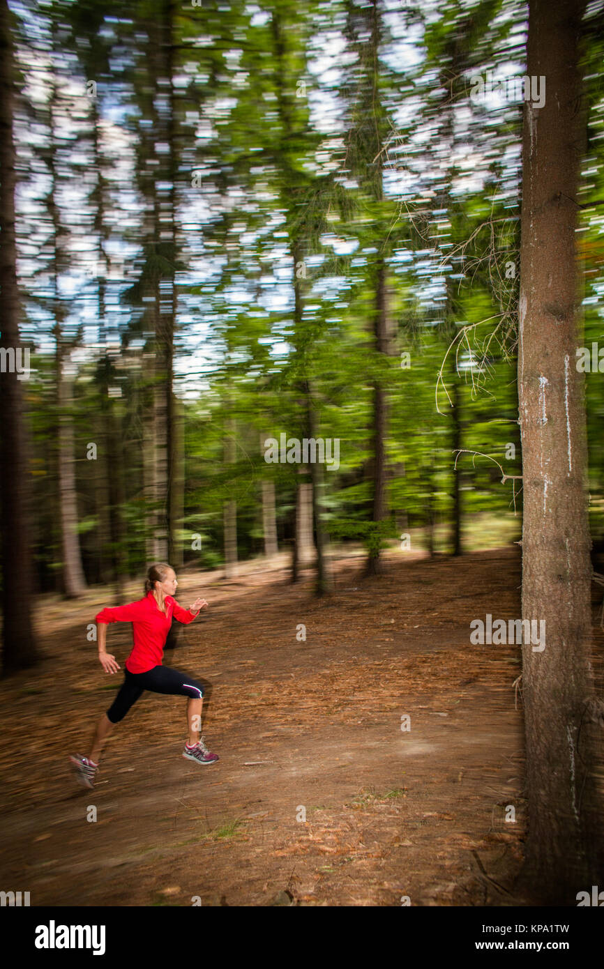 Young woman running outdoors in a forest, going fast (motion blurred ...
