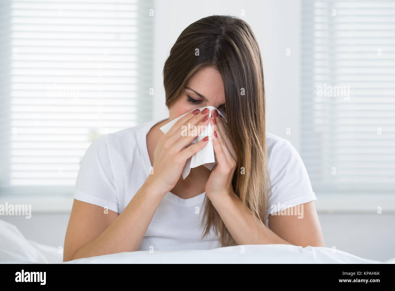 Woman With Cold Blowing Her Nose Stock Photo - Alamy