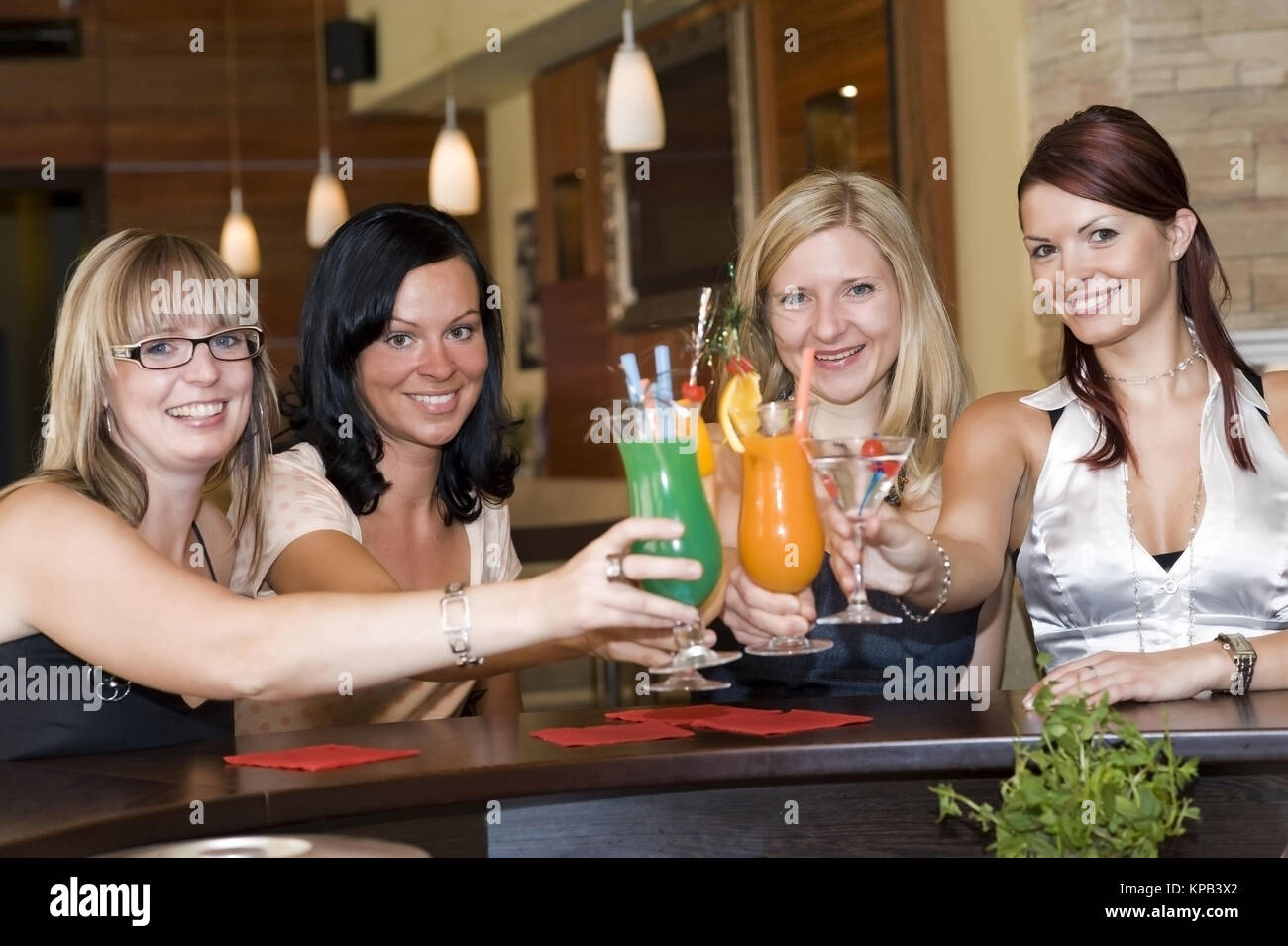 Model release, Vier junge Frauen sitzen mit Cocktails an der Bar - four ...